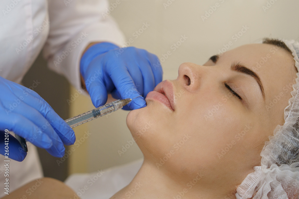 Aesthetic cosmetology. Lip augmentation in spa salon. Beautician makes ...
