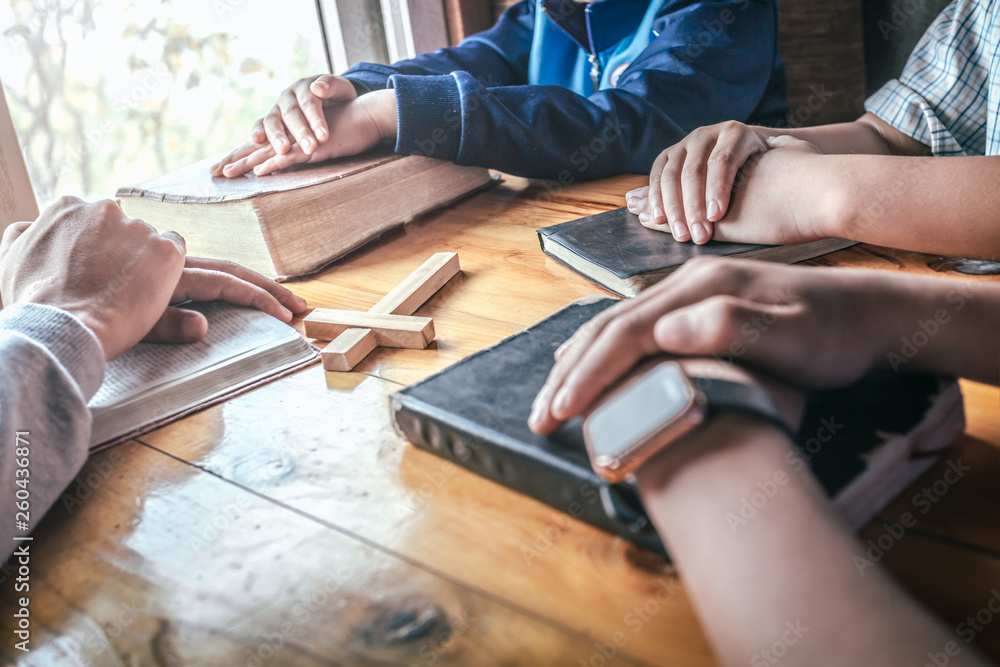 Children group praying together around wooden table with open bible ...