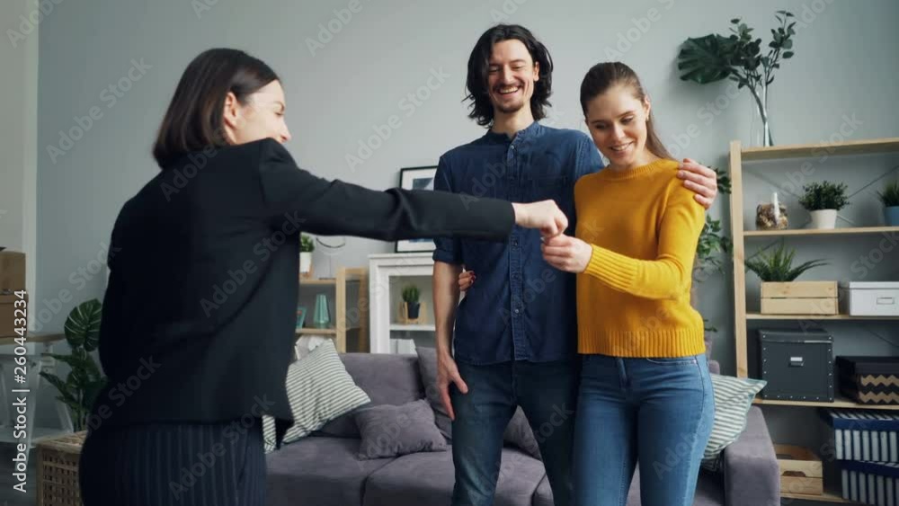 Housing agent is giving keys to buyers of new apartment, happy husband ...