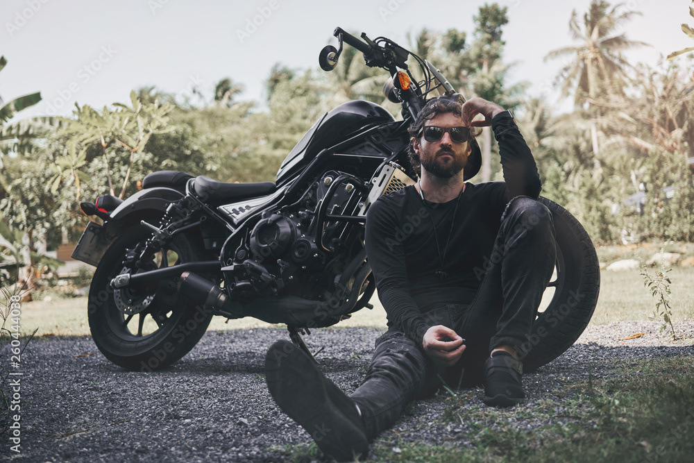 Handsome biker man in black wear sit near classic style cafe racer ...