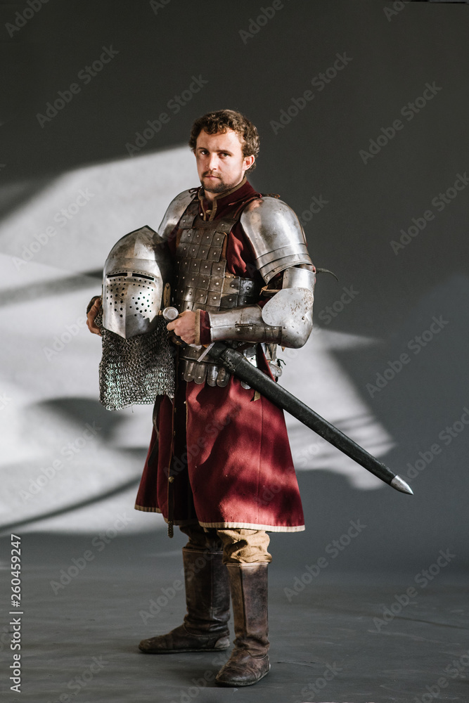 Medieval man knight in armor and weapon on dark background. Portrait of ...