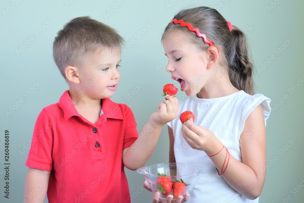 Two little Caucasian kids eat strawberries. Brother and sister eating ...