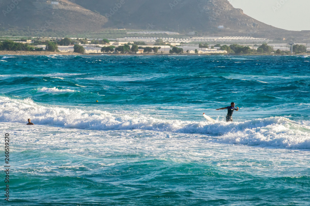 Greece, Crete, August 2018: Young man, beginner Surfer learns to surf ...