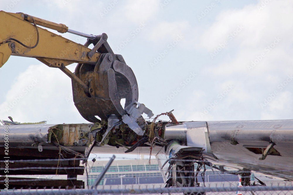 Aircraft wing section being reduced to scrap by a demolition excavator ...