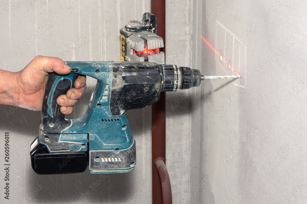 man with cordless hand drill drilling a hole in concrete with a laser ...