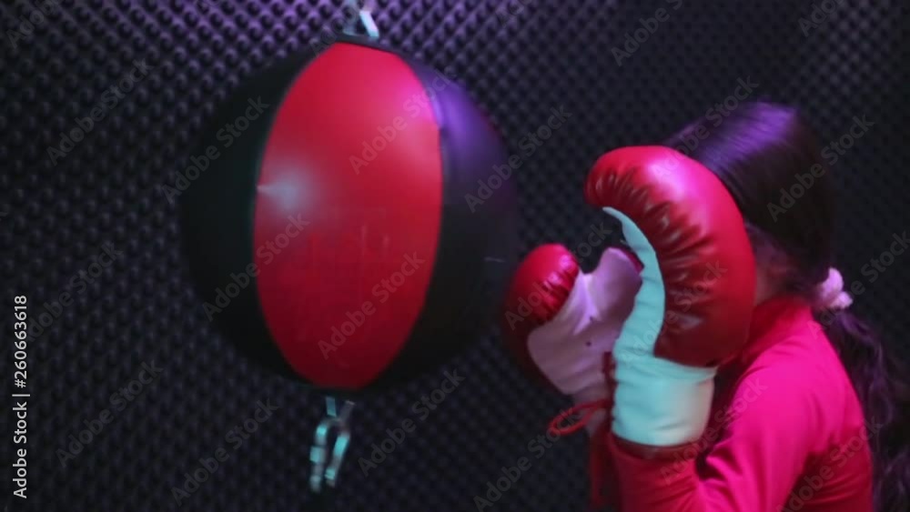 Little girl in red boxing gloves punching double end striking bag ...
