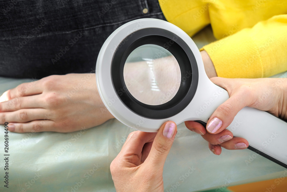 Dermatologist using a professional magnifying glass while doing skin ...