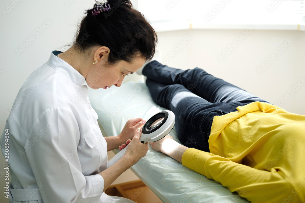 Dermatologist using a professional magnifying glass while doing skin ...