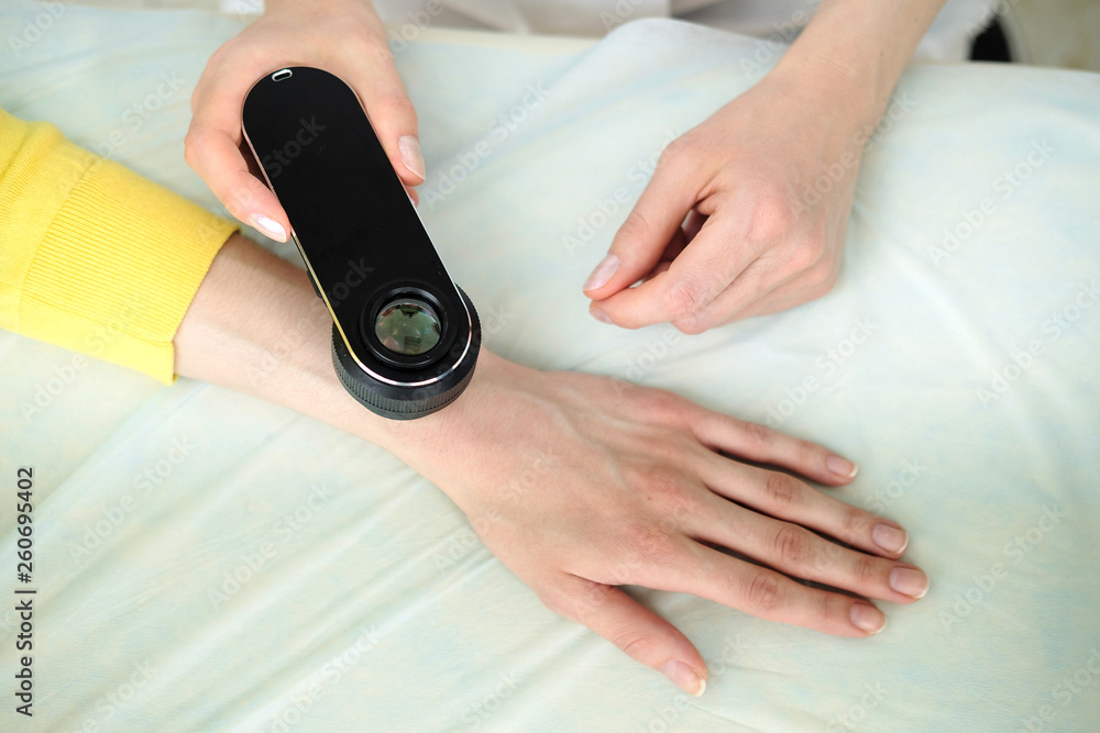 Female dermatologist using a professional dermatoscope while doing skin ...