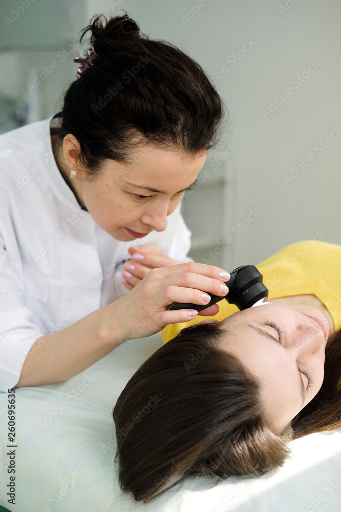 Female dermatologist using a professional dermatoscope while doing skin ...