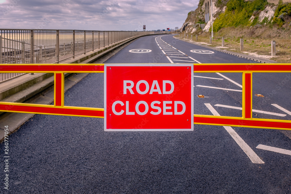 Red road closed barrier across an empty tarmac road with white road ...