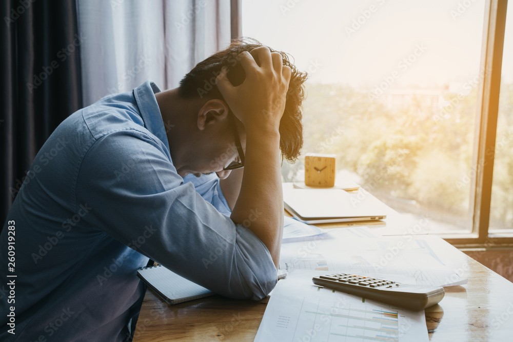 Stressed businessman.A young man sits at his Desk and holds his hands ...