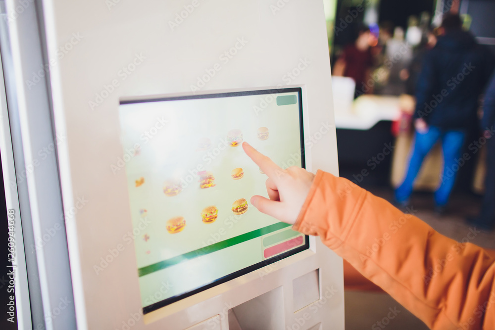 A man orders food in the touch screen terminal with electronic menu in ...