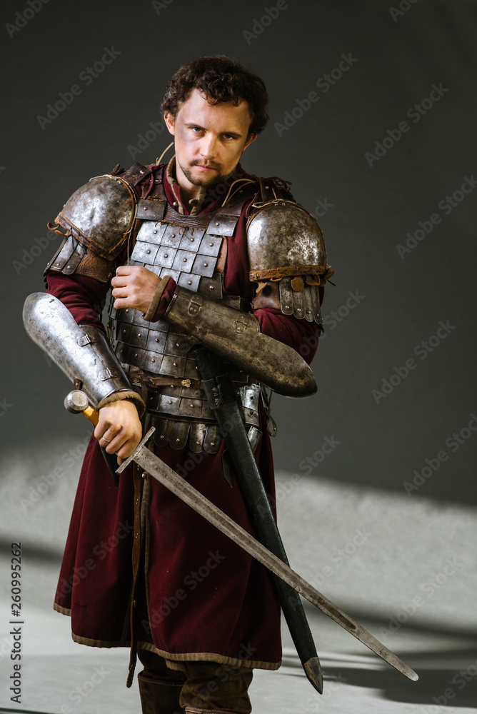 Medieval man knight in armor and weapon on dark background. Portrait of ...