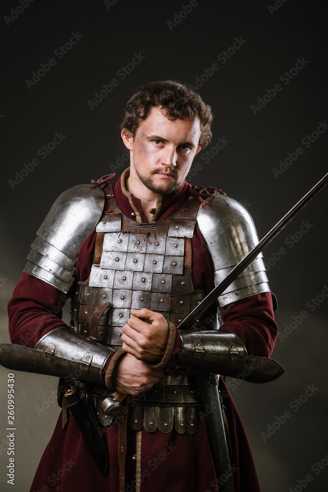 Medieval man knight in armor and weapon on dark background. Portrait of ...