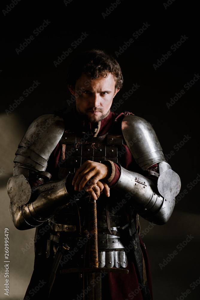 Medieval man knight in armor and weapon on dark background. Portrait of ...