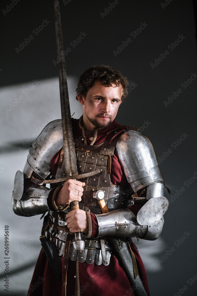 Medieval man knight in armor and weapon on dark background. Portrait of ...