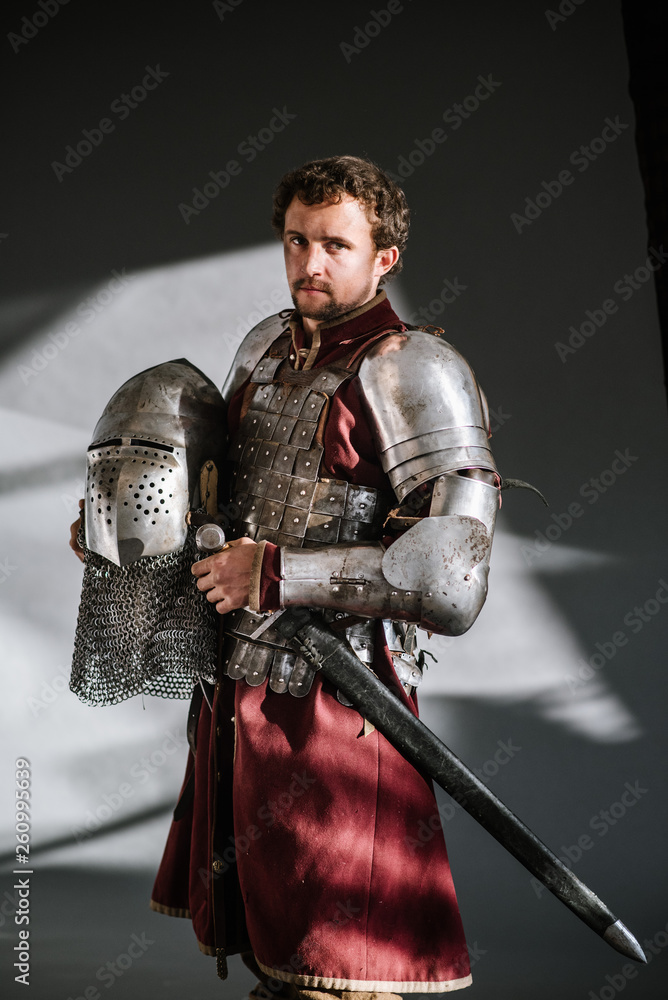 Medieval man knight in armor and weapon on dark background. Portrait of ...