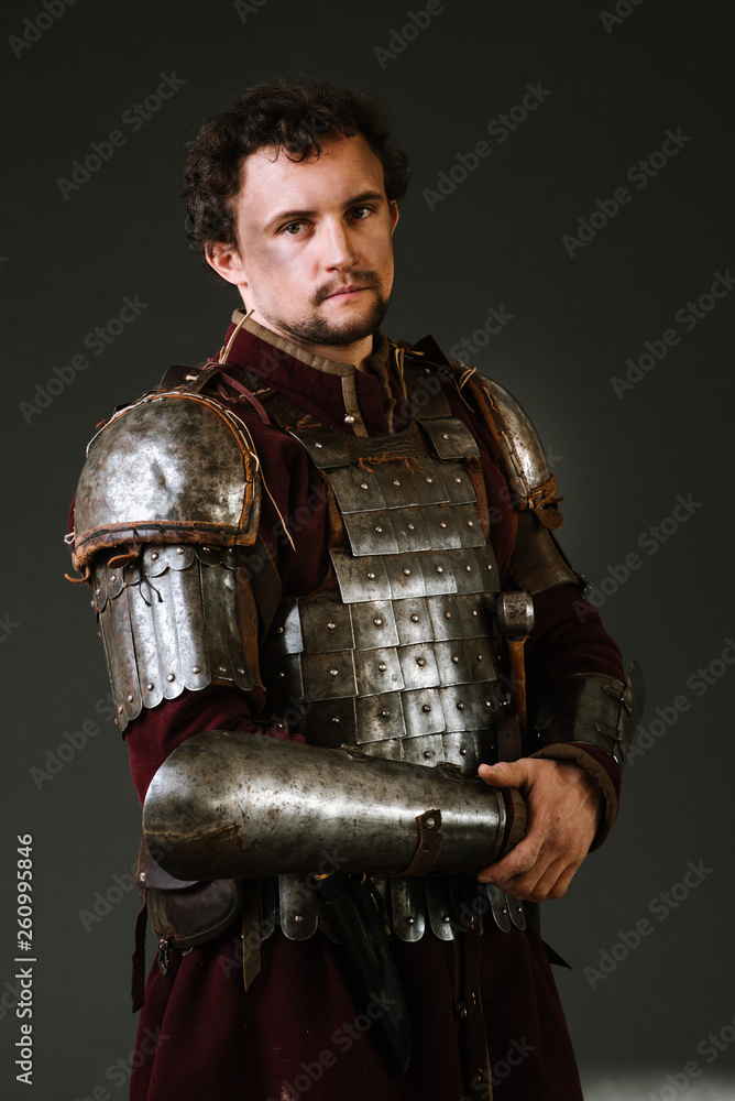 Medieval man knight in armor and weapon on dark background. Portrait of ...