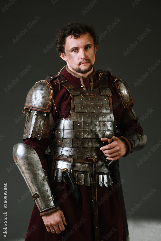 Medieval man knight in armor and weapon on dark background. Portrait of ...