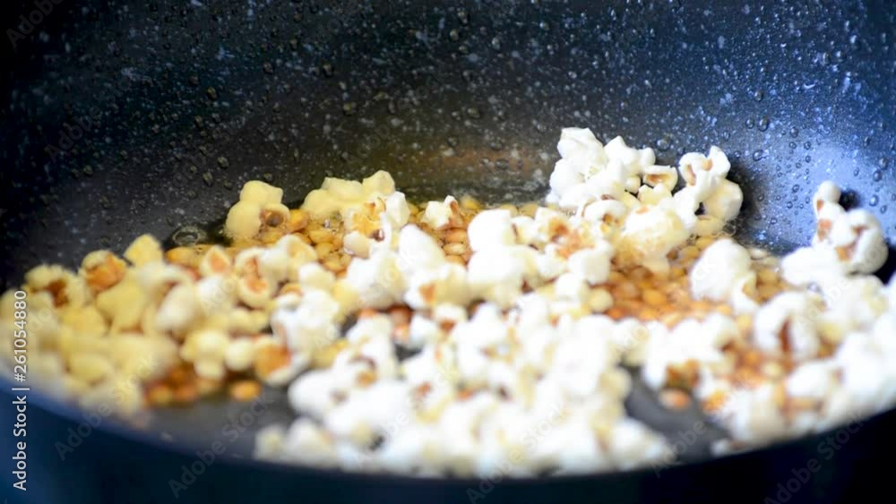 Popcorn in hot oil in a Teflon pan close-up Popcorn is boiled in hot ...
