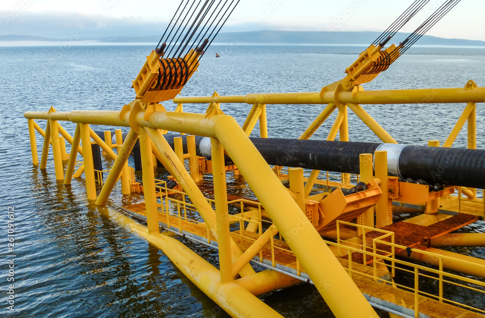 Laying of pipes with pipe-laying barge crane near the shore. Descent of ...