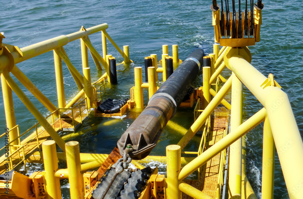 Laying of pipes with pipe-laying barge crane near the shore. Descent of ...
