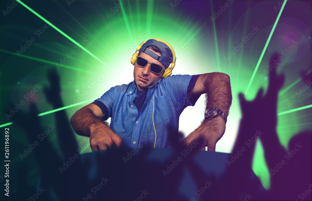 young happy and cool DJ playing music at party event in night club ...