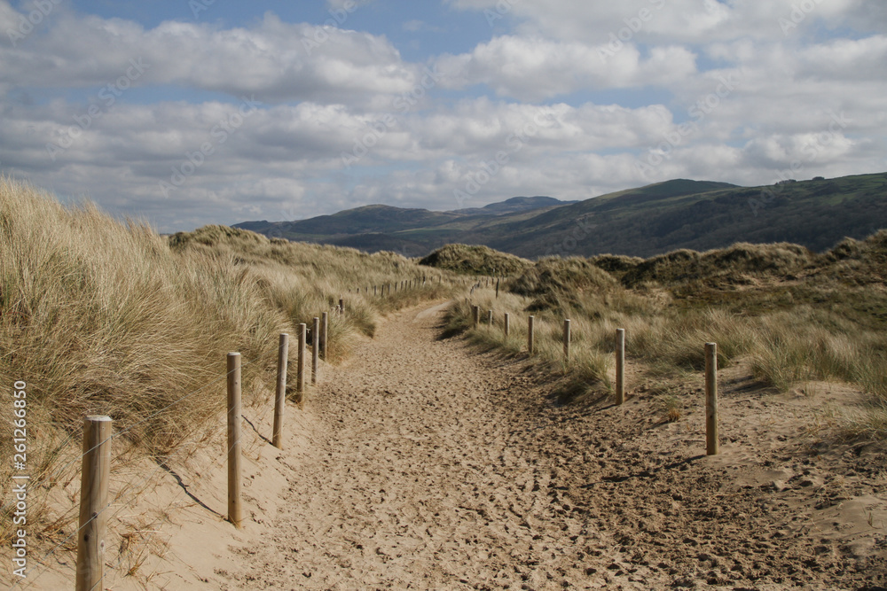 Curved sand pathway with marram grass through to green mountains Stock ...