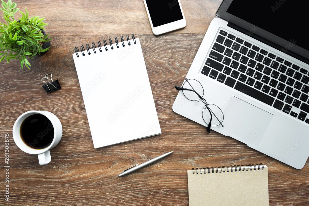 Blank notebook page is on top of wood office desk table with laptop ...