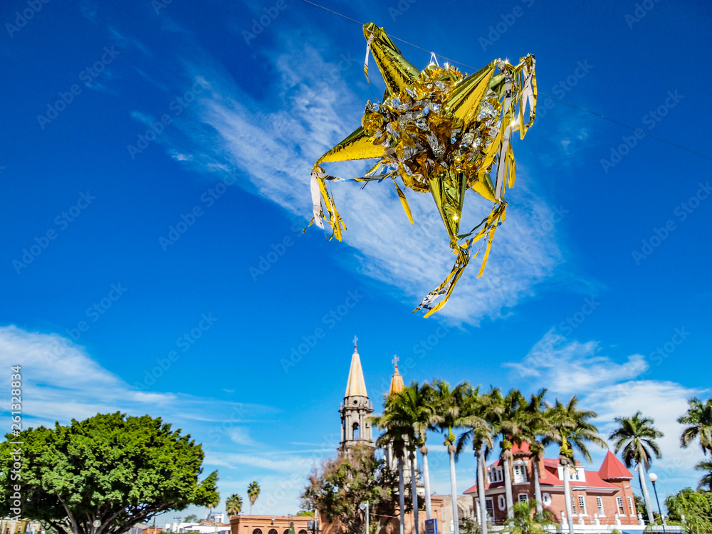 Big gold and silver coloured Piñata against a blue sky with white ...