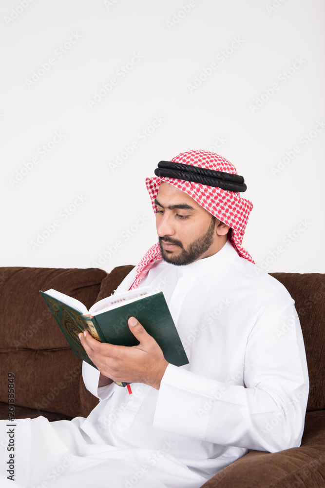 Arab Muslim man sitting on sofa chair and reading the holy Quran Stock ...