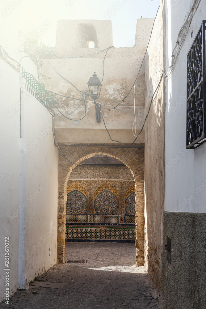 Walkway with arch between stone constructions on street in sunny day in ...