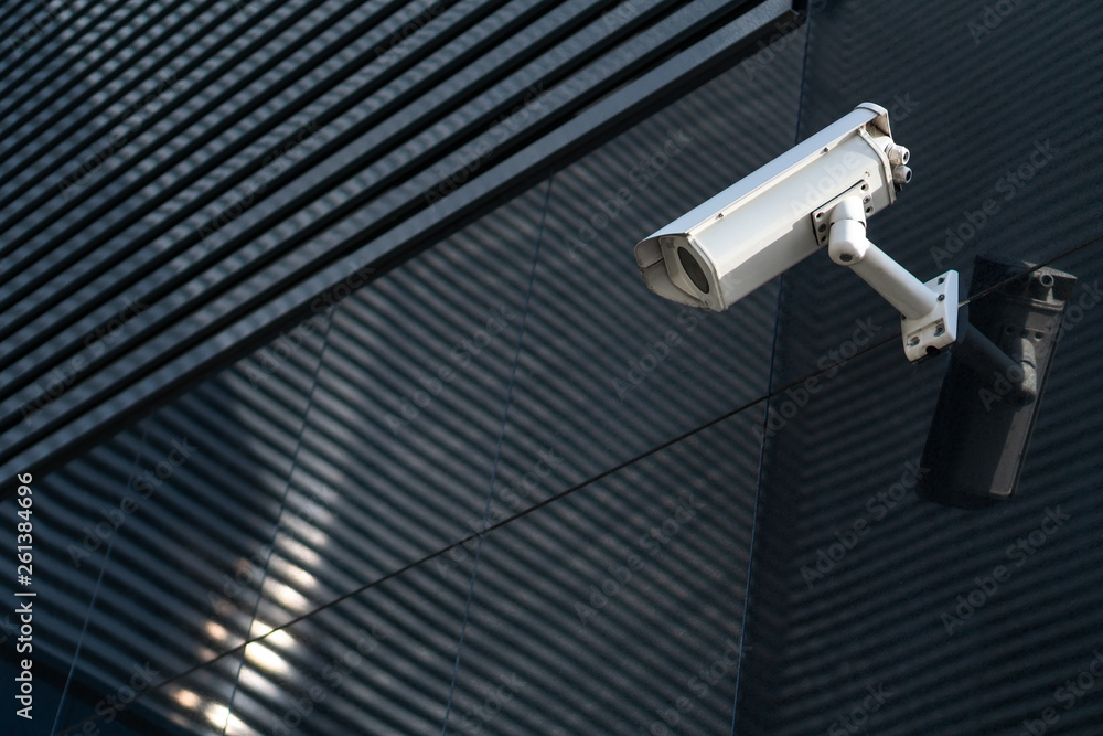 Modern CCTV camera on a wall. A blurred night cityscape background ...