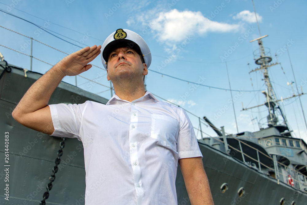 avy officer standing beside warship and do salute.The captain in white ...