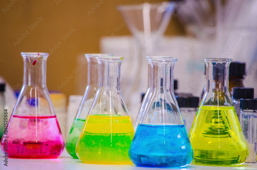 Multiple colorful solution in conical flask on a bench in a chemistry ...