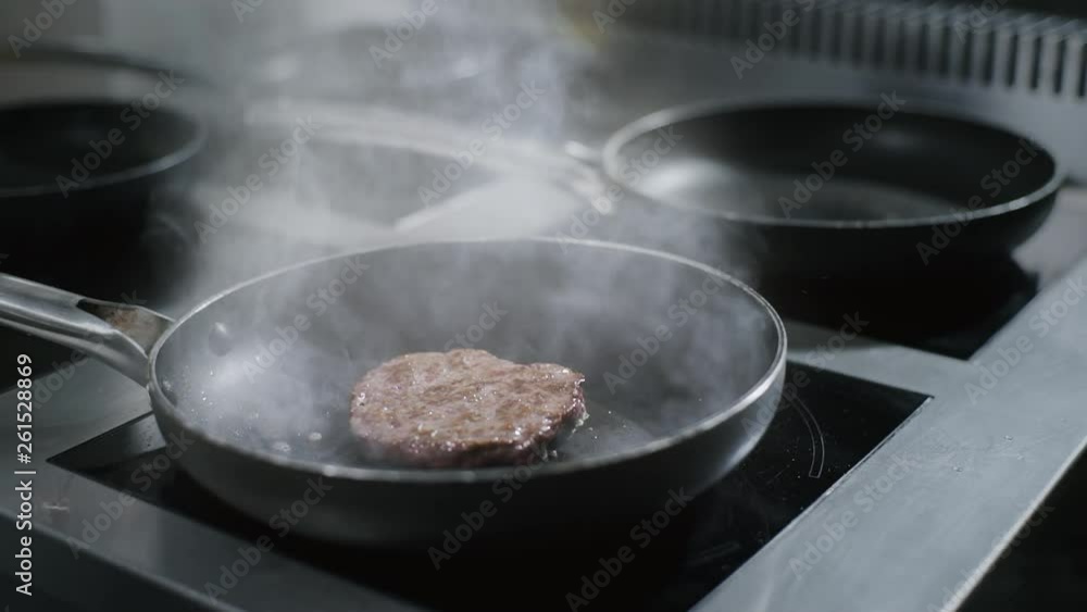 Chef puts raw beef cutlet to the hot pan at the restaurant kitchen in ...