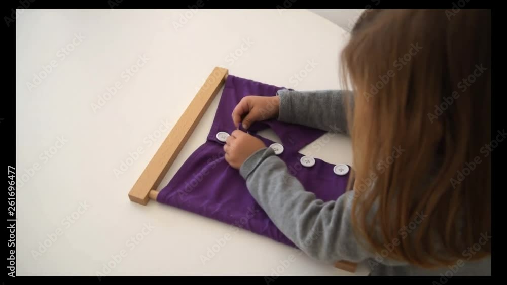 Little student girl of montessori pedagogy working with the buttoning ...