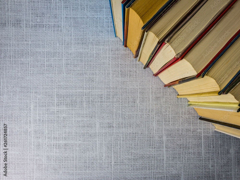 Vintage books stacked side by side framing open white fabric background ...