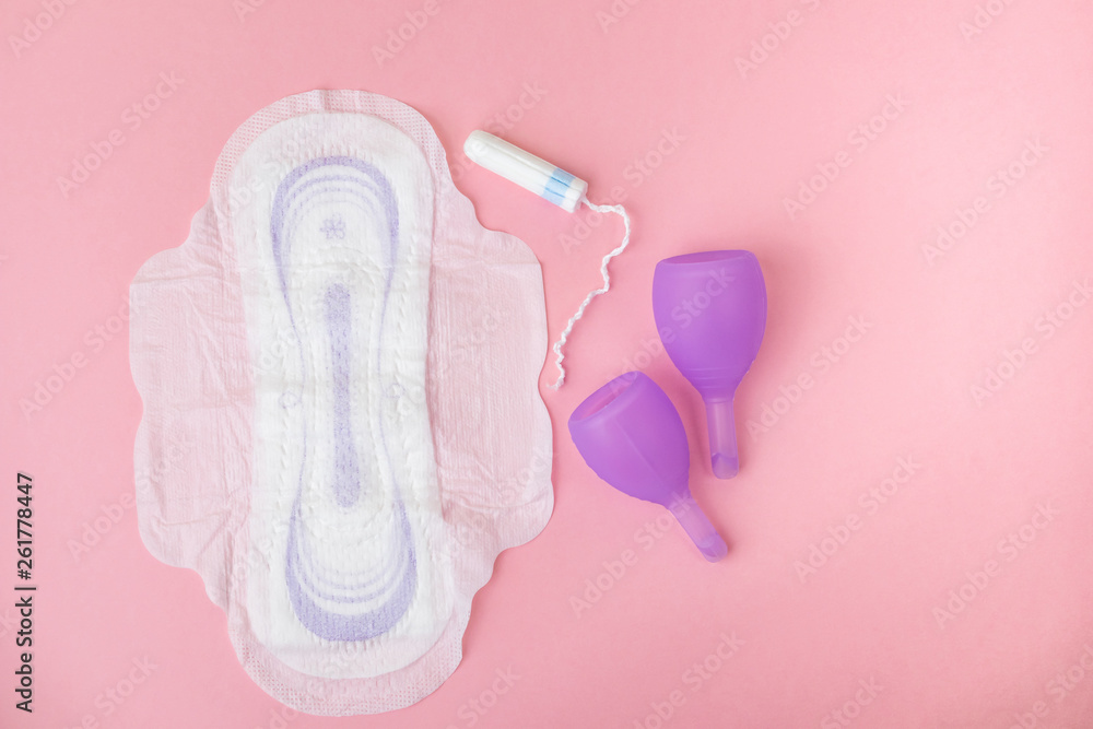 Purple menstrual cup, tampon and Sanitary napkin are on a pastel pink ...