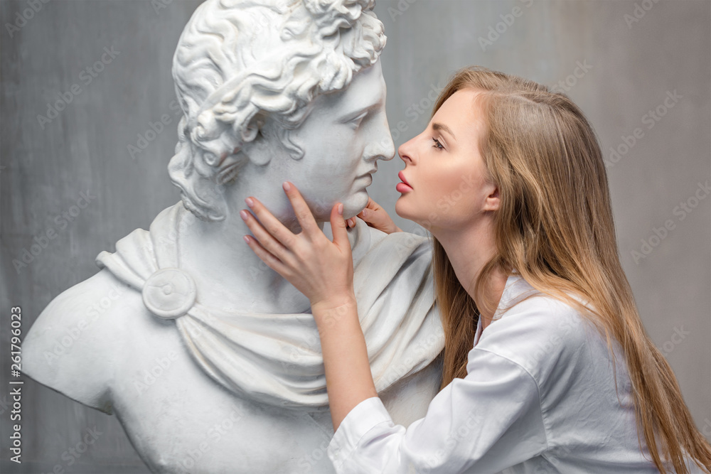 Young woman kissing God Apollo bust sculpture. Ancient Greek god of Sun ...