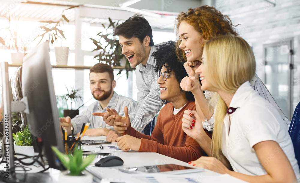 Young team looking at computer screen in office together Stock Photo ...