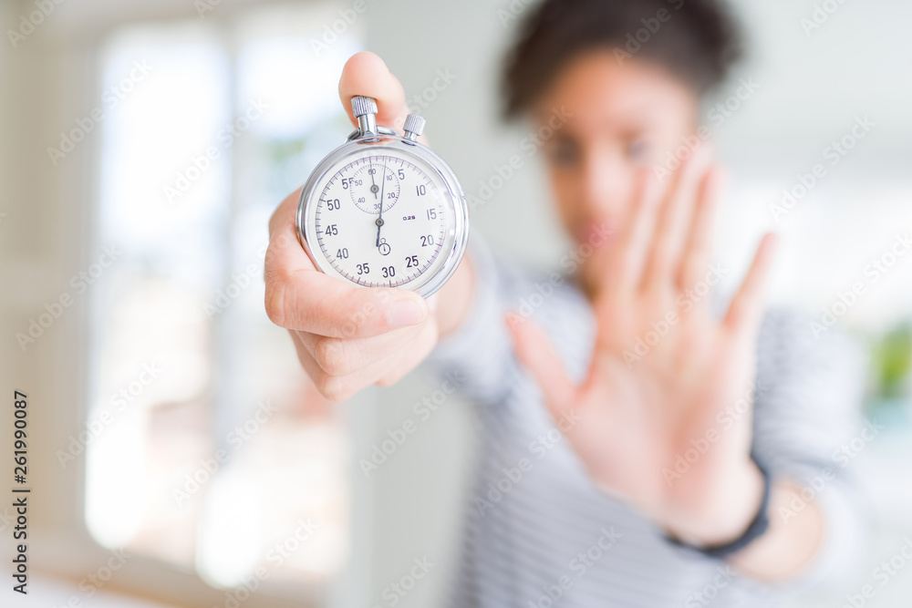 Young african american woman holding stopwatch with open hand doing ...