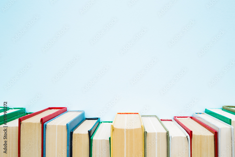 Row of old books with colorful covers on pastel blue background ...