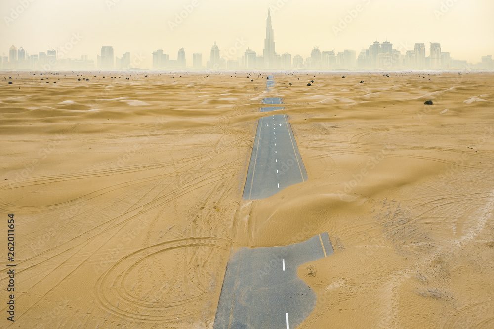 Aerial view of a deserted road covered by sand dunes in the middle of ...