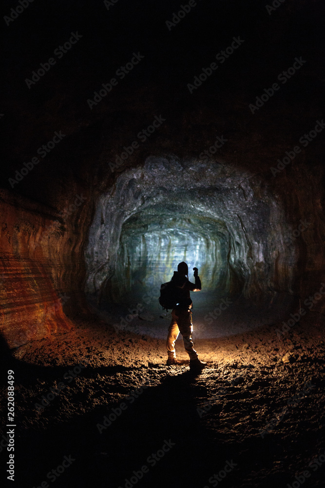 A male caver holding a propane lantern and flashlight while exploring ...