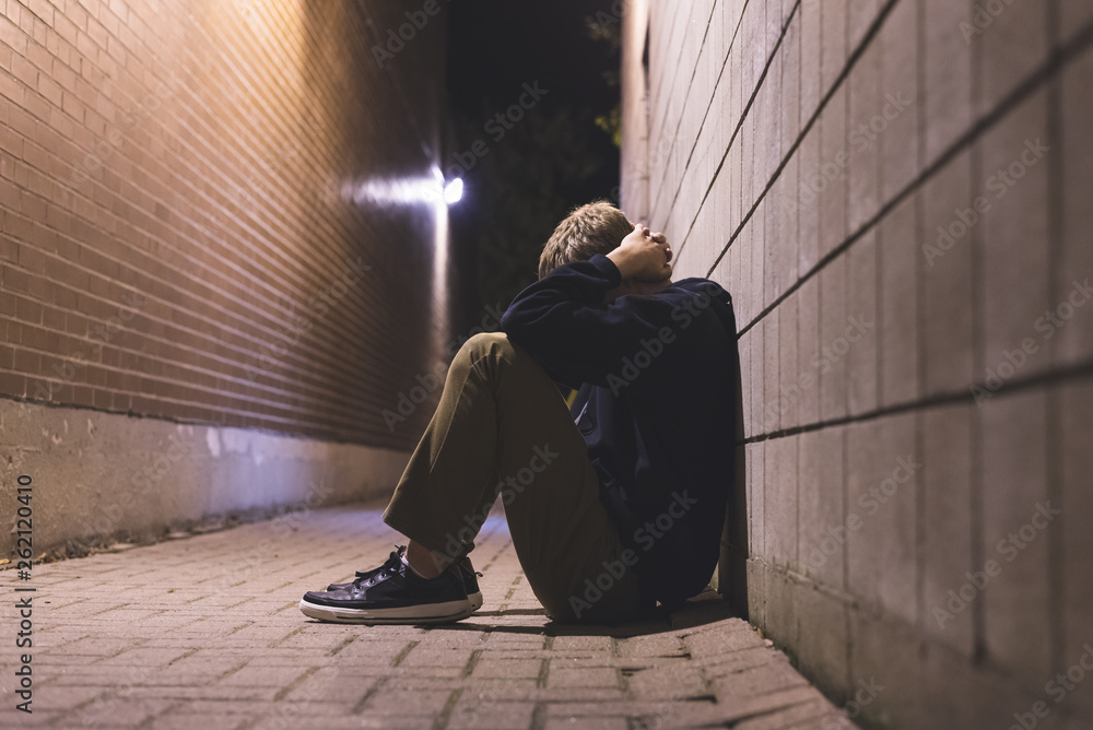 Sad teen sitting in an alleyway all alone at night. Stock Photo | Adobe ...