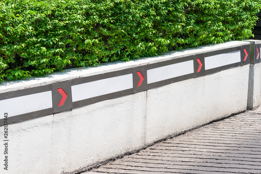 Incline ramp to car parking with green bushes, Red arrow sign for ...