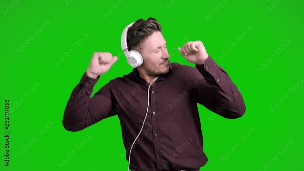 Bearded man enjoy listening to music using headphone with green screen ...