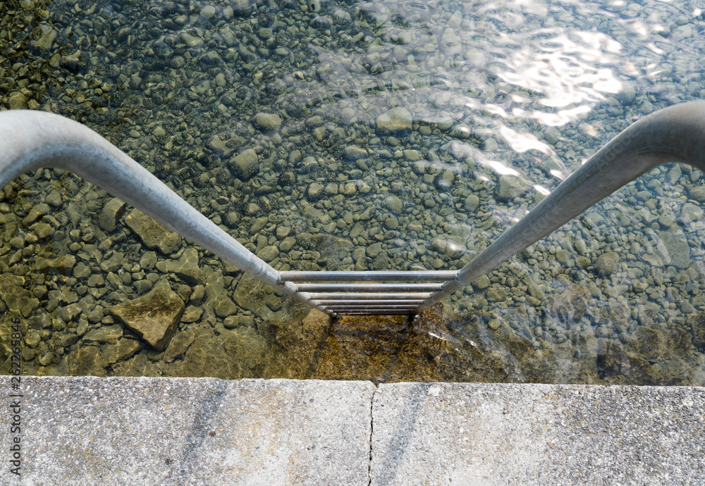 tall long curved metal stairs leading from a harbor wall down into the ...